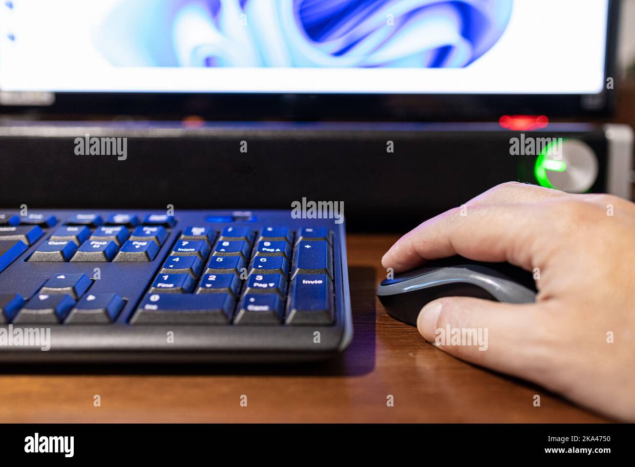 Selective focus on a hand that is clicking on a mouse with monitor and ...