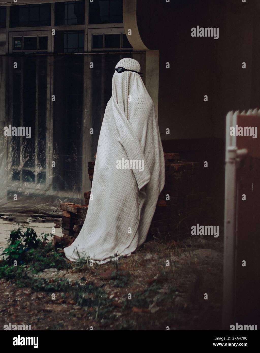 A view of human with black glasses in white ghost costume standing near ...