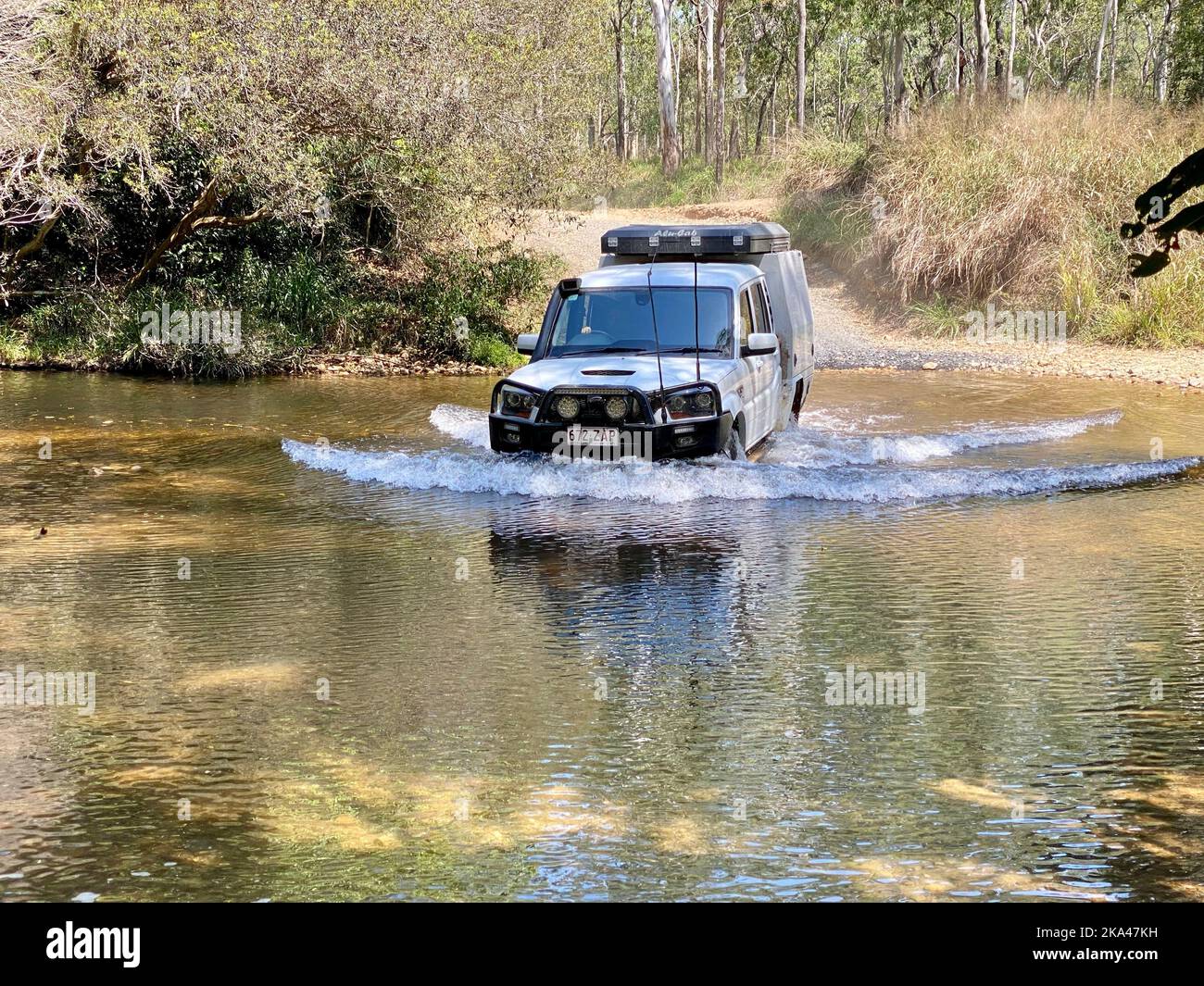 A white 4WD crossing a river in the rainforest in North Queensland ...