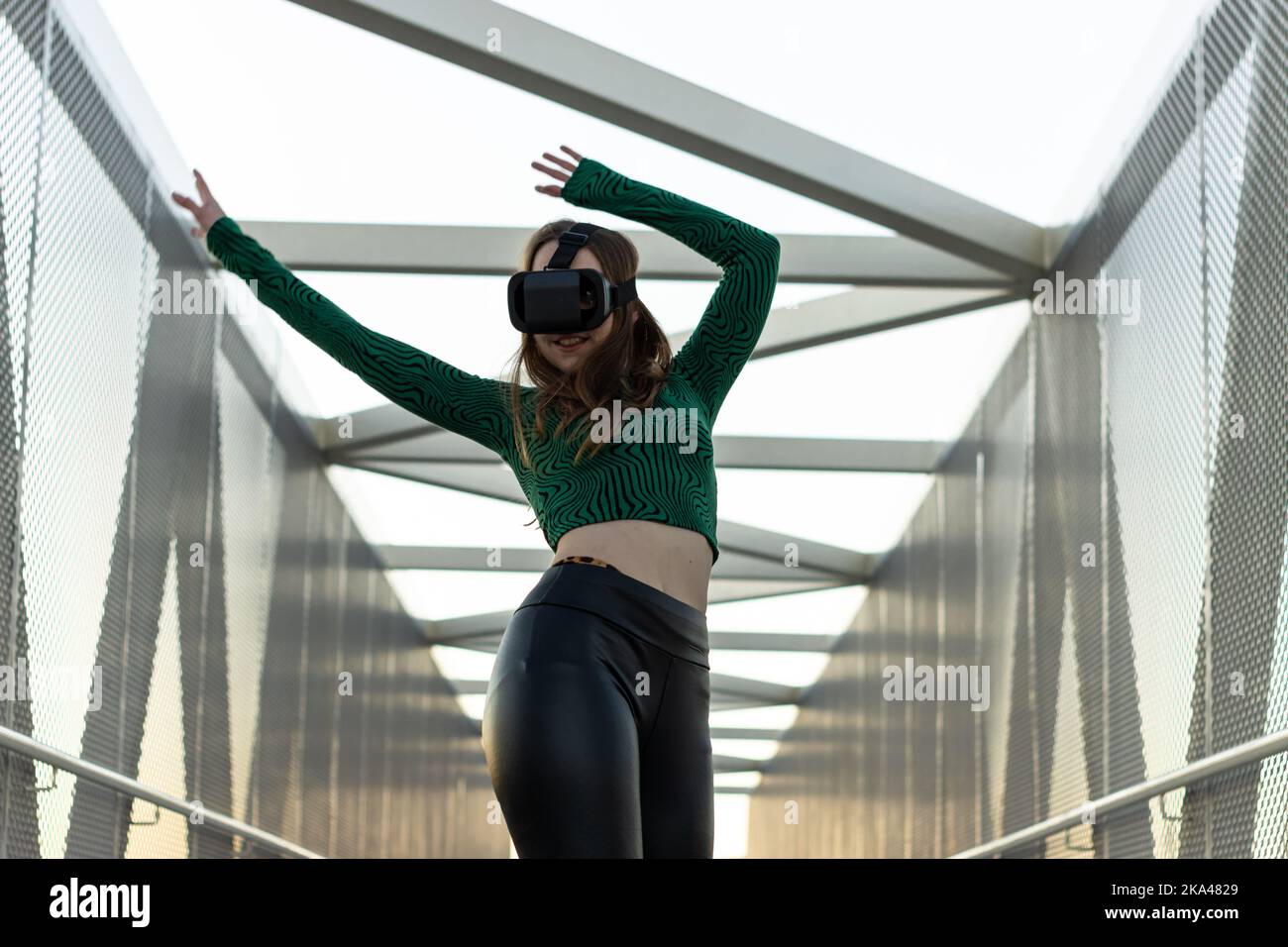 A charming cheerful young woman dancing and wearing a VR box on the ...