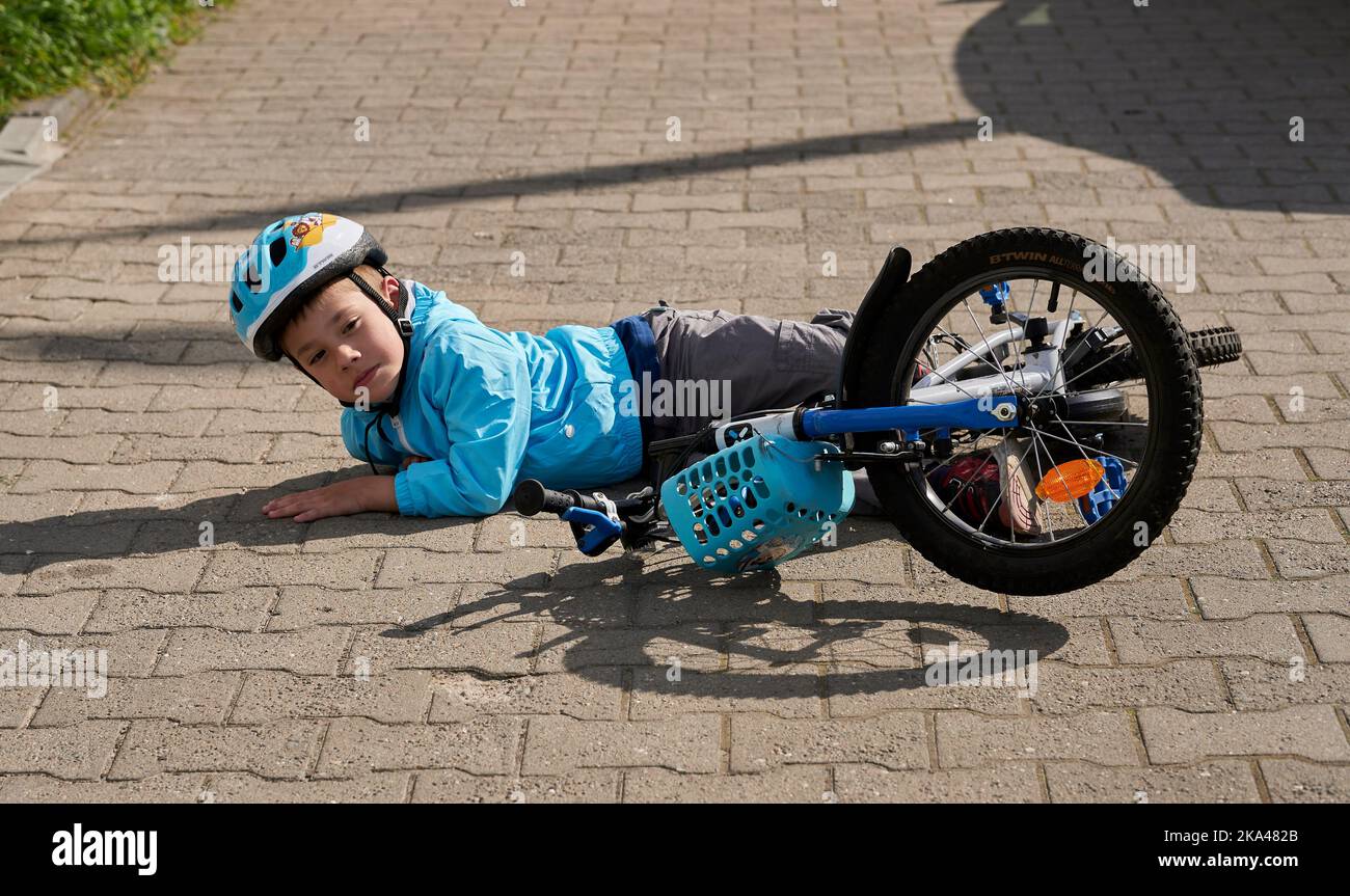 A boy child with safety helmet fell off a bicycle in the park Stock ...