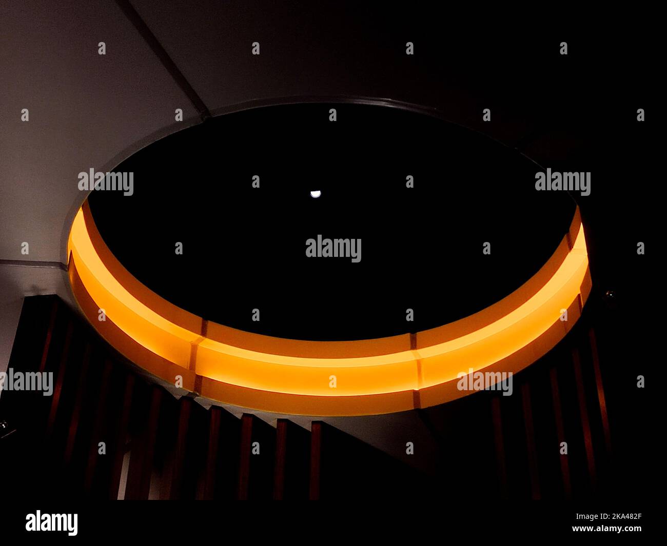 A low angle shot of a round glass ceiling with an orange LED lighting ...