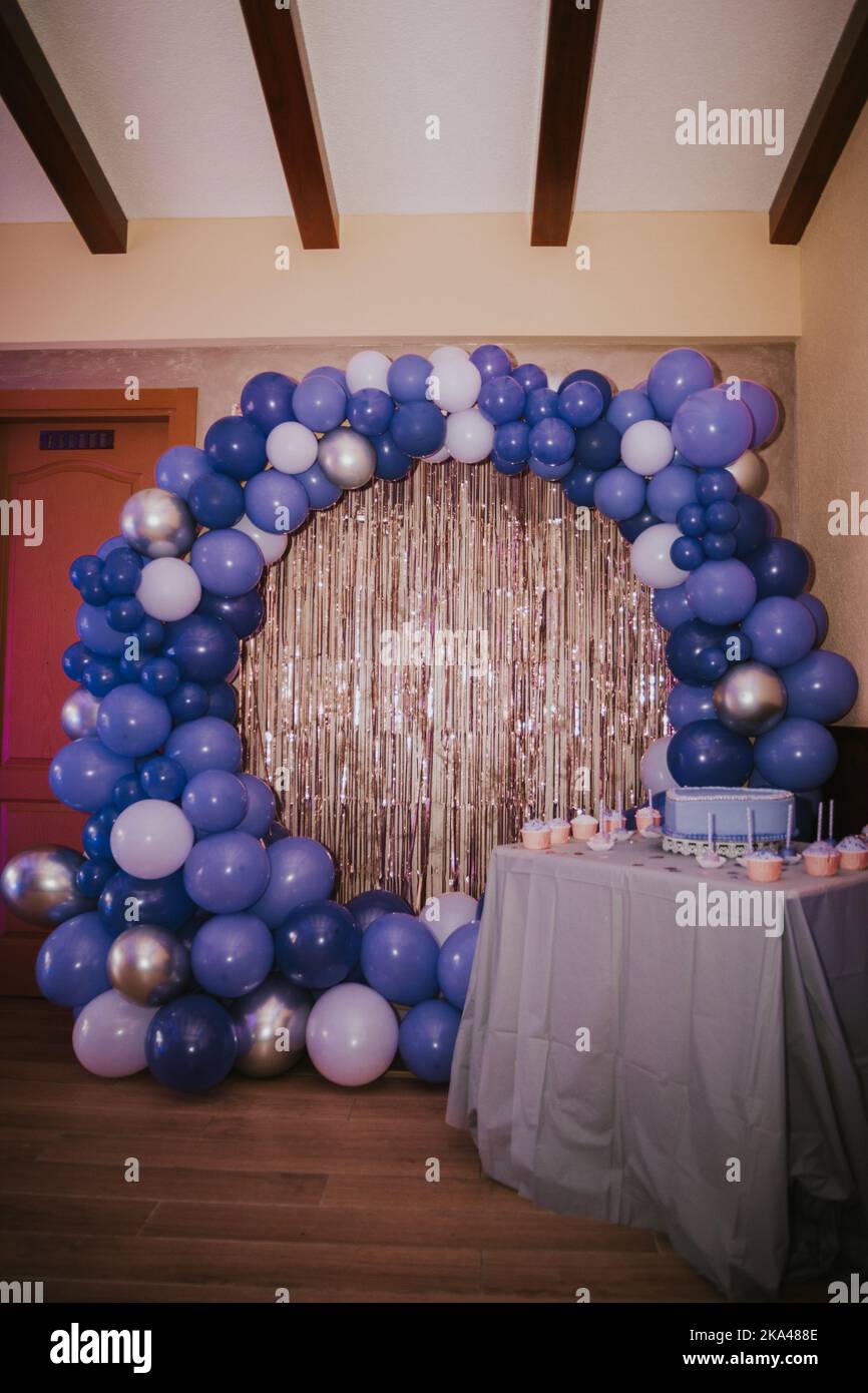 A vertical shot of blue balloons, birthday decorations, and cupcakes ...