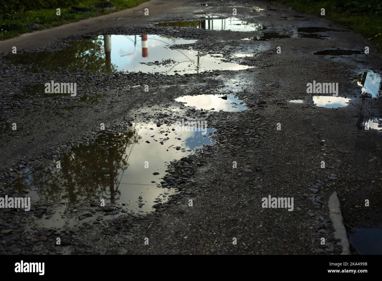 Large puddle on asphalt. Road with pits. Puddles on road. Rural highway ...