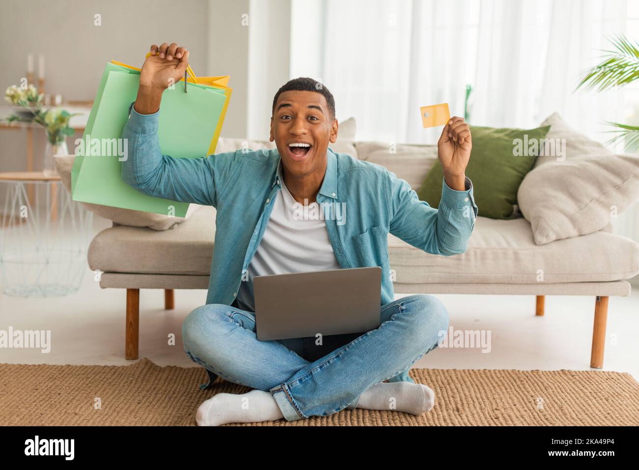 Excited happy millennial african american male with bags and credit ...