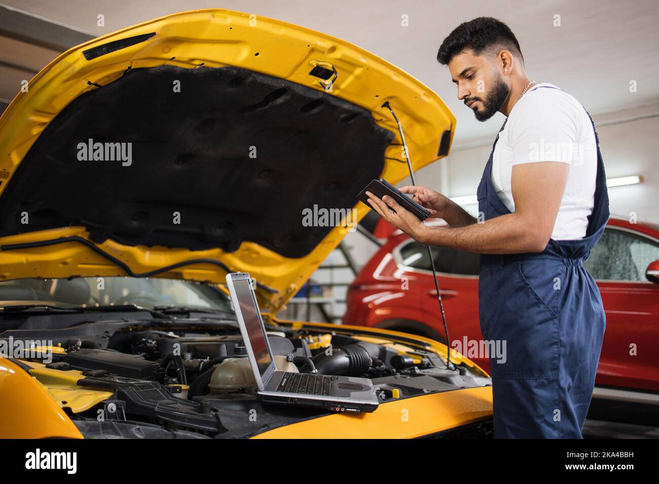 Serious focused man car technician mechanic repairing car problem of ...