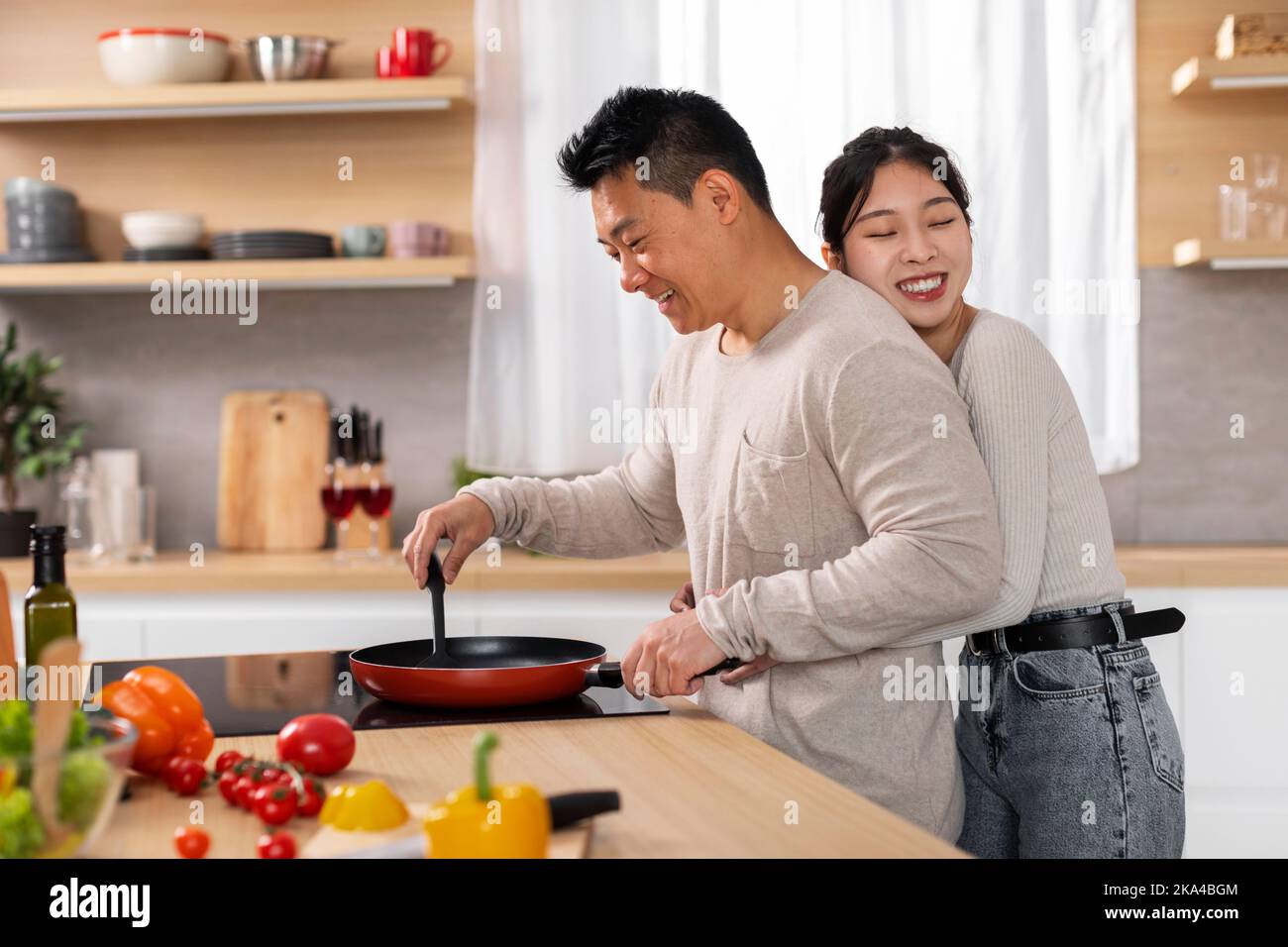 Loving asian woman hugging her boyfriend cooking meal Stock Photo - Alamy