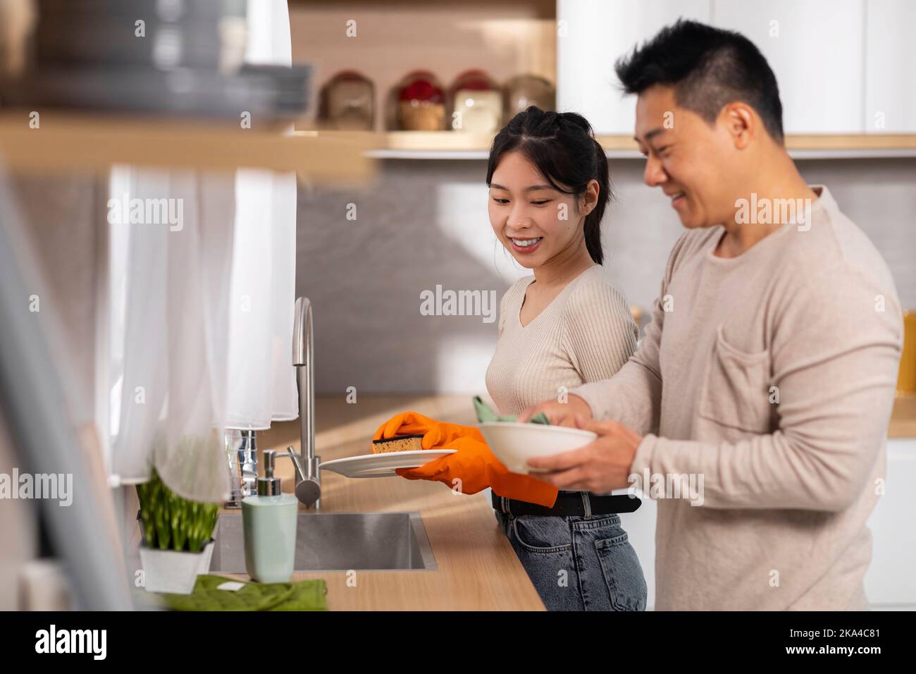 Happy asian spouses doing chores together, washing dishes Stock Photo ...