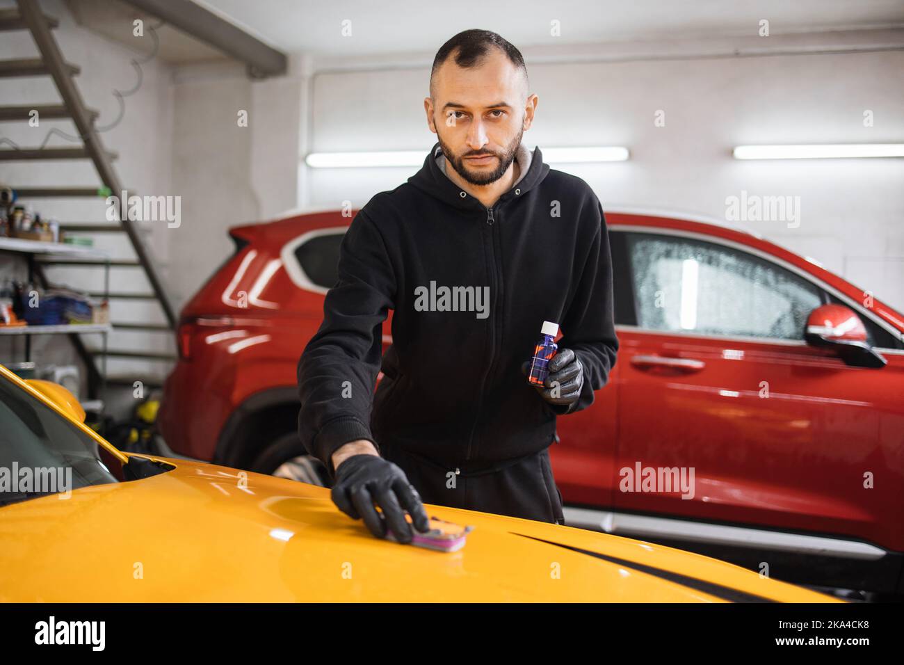 Young man, car polish service worker polishing car hood, buffing and ...