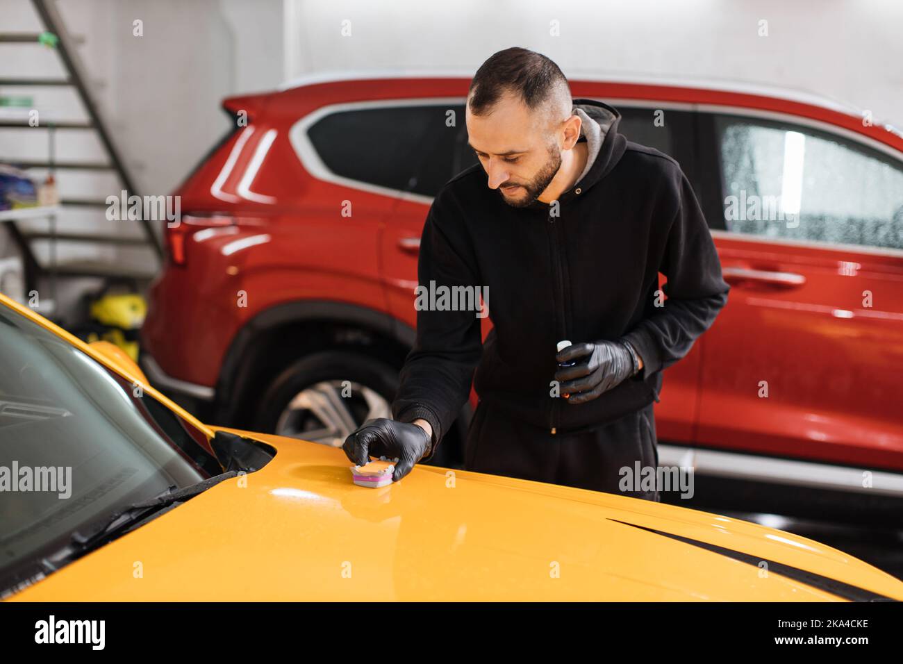 Young man, car polish service worker polishing car hood, buffing and ...