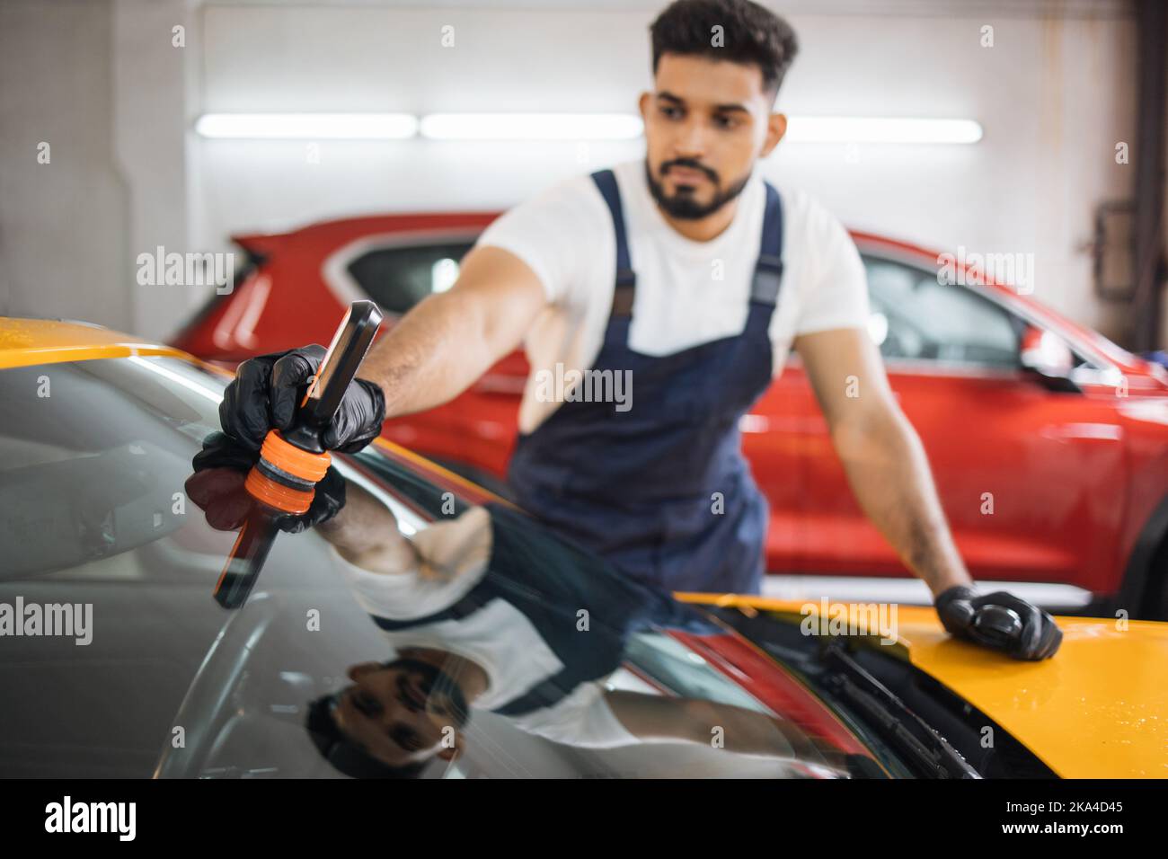 Male bearded worker in blue overalls and protective gloves, on a ...