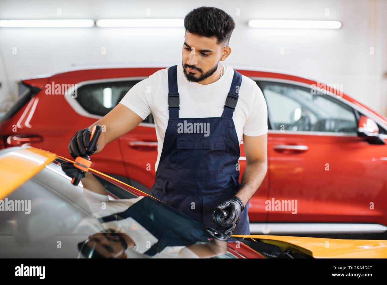 Male bearded worker in blue overalls and protective gloves, on a ...