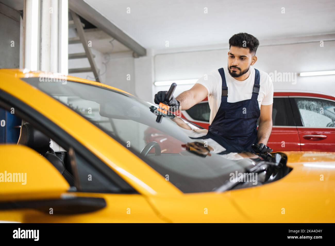 Male bearded worker in blue overalls and protective gloves, on a ...
