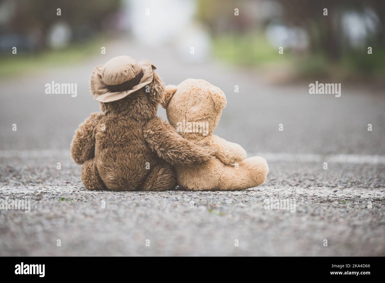 One teddy bear supporting a smaller teddy bear on the street. Love ...