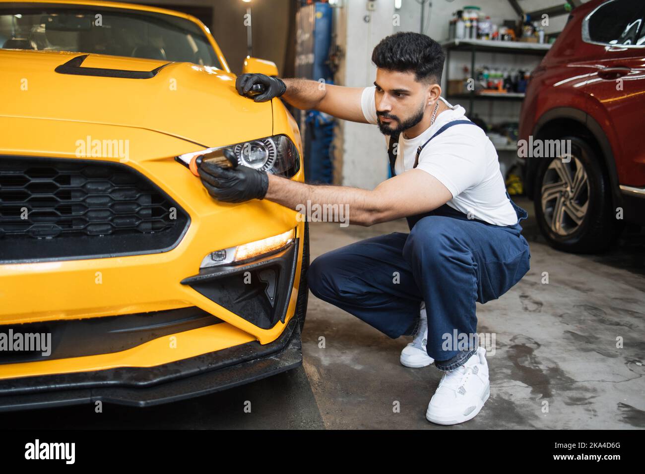 Male bearded worker in blue overalls and protective gloves, on a ...