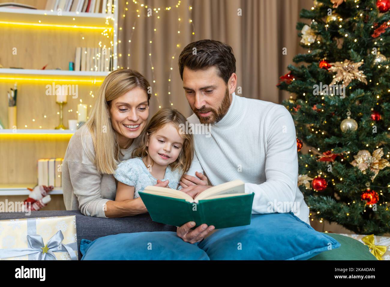 A young family spends time together on Christmas Eve. Mom and dad are ...