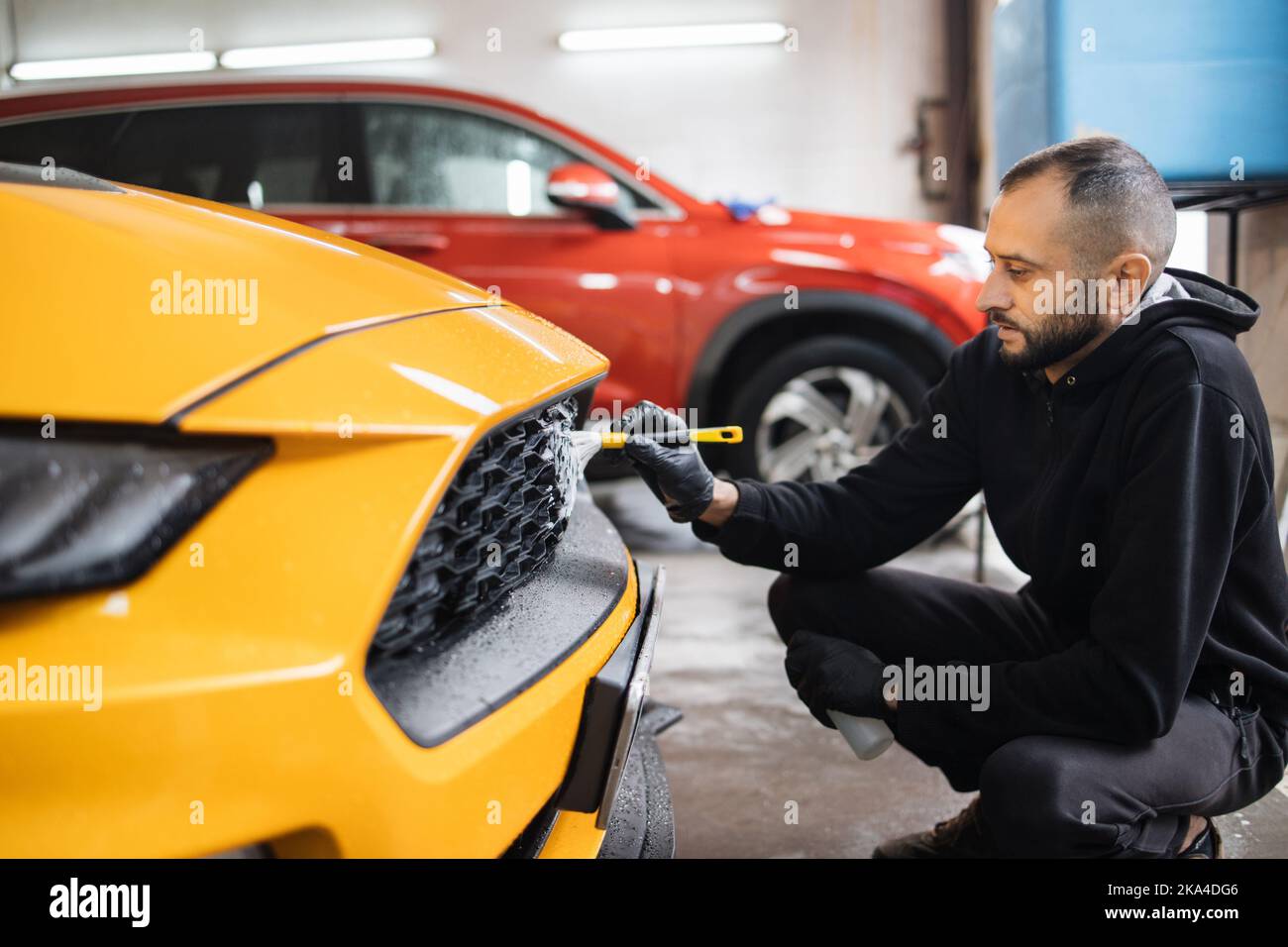 Car detailing wash. Manual cleaning with soap at car wash. Portrait of ...