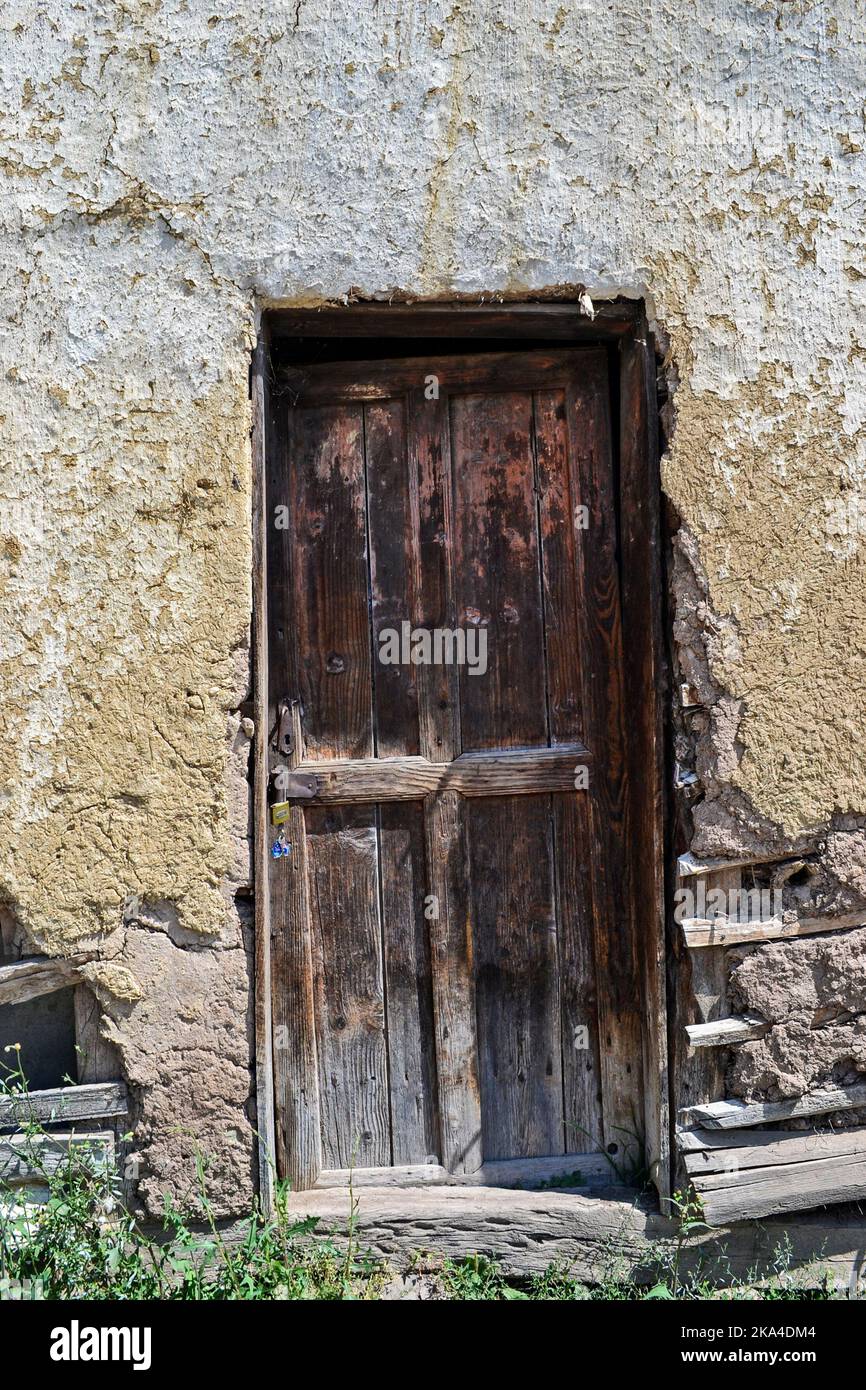A vertical of a weathered worn out wooden door of a semi collapsed ...