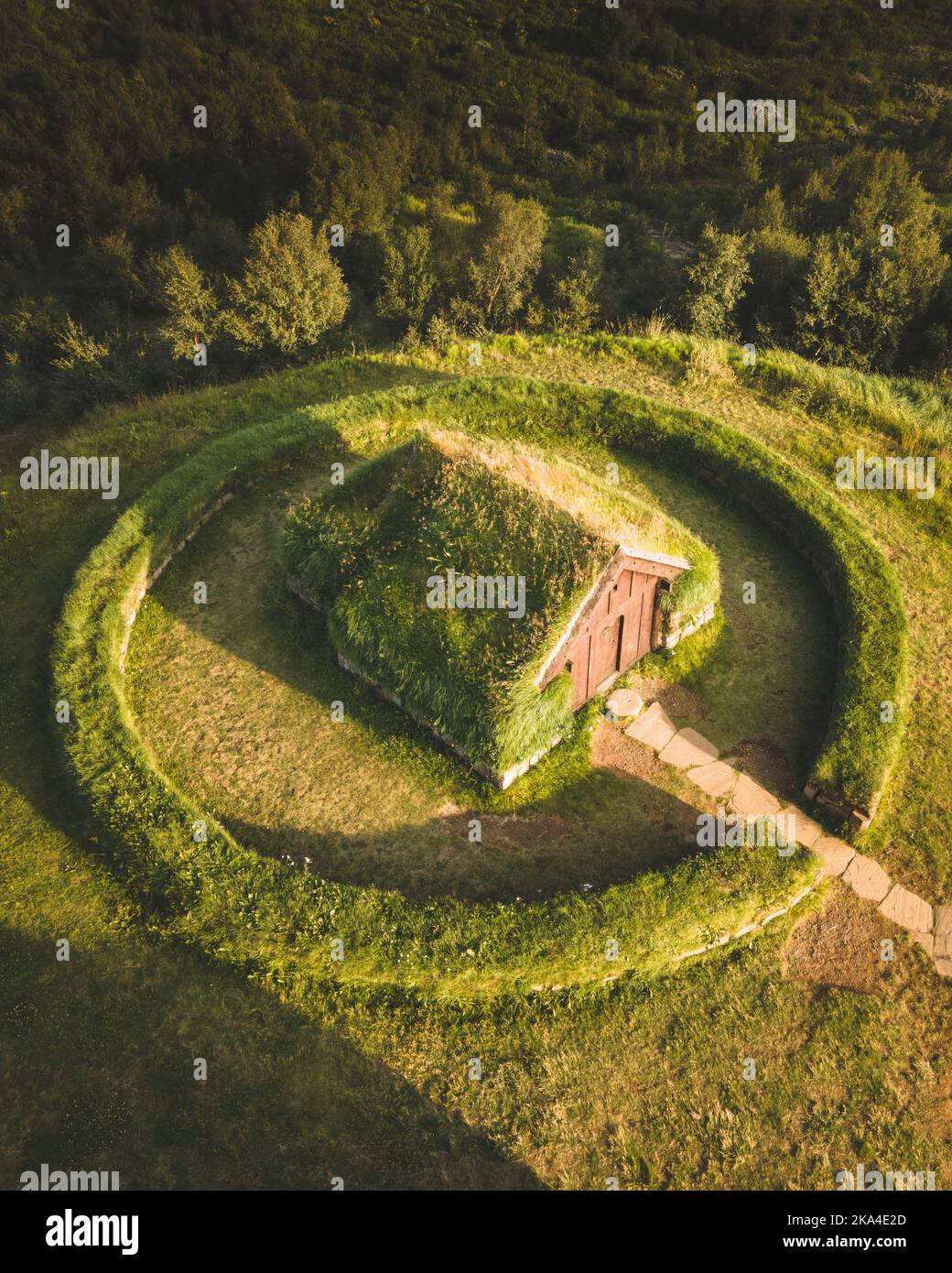 An aerial shot of circle shape grass with an old cabin covered with ...