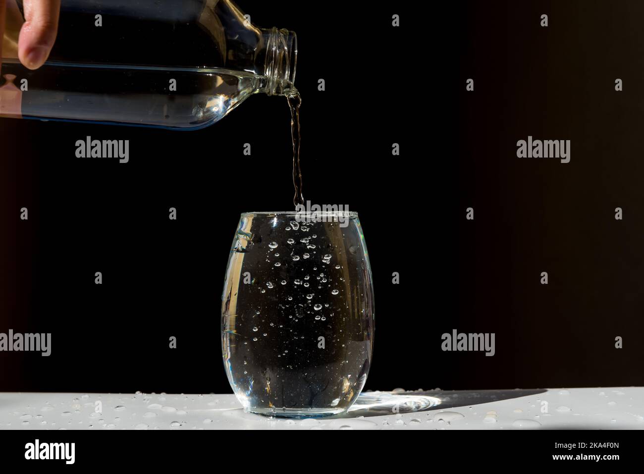 A closeup of a hand pouring water from a bottle into a glass Stock ...