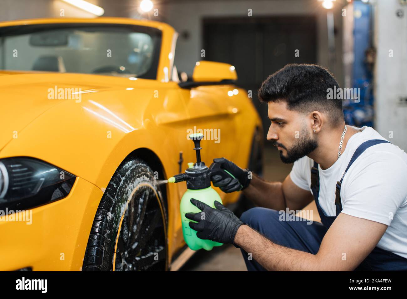 Washing a car in detailing service. Indoor shot of male worker in ...