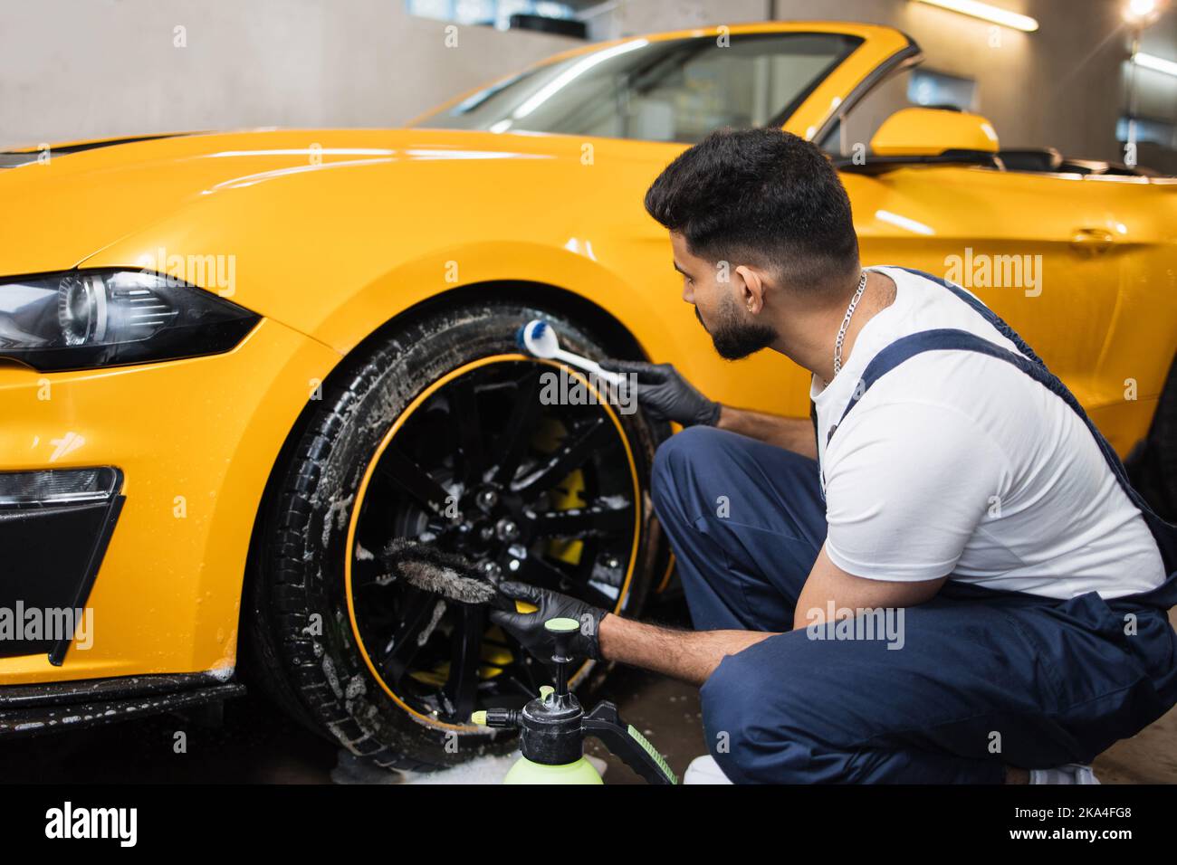 Car washing and detailing workshop. Bearded man worker in protective ...