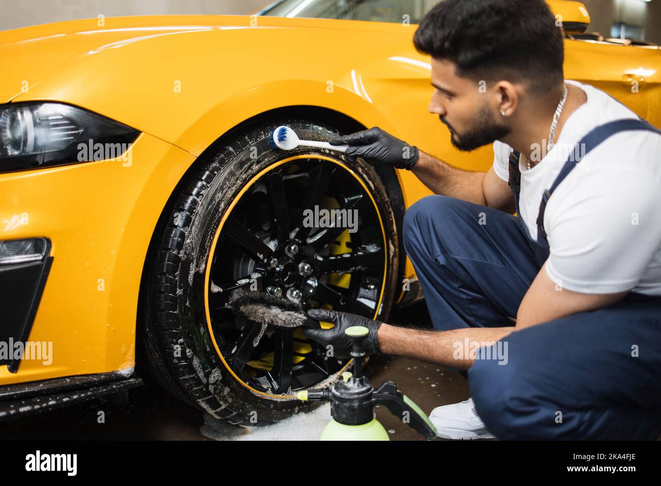 Car washing and detailing workshop. Bearded man worker in protective ...