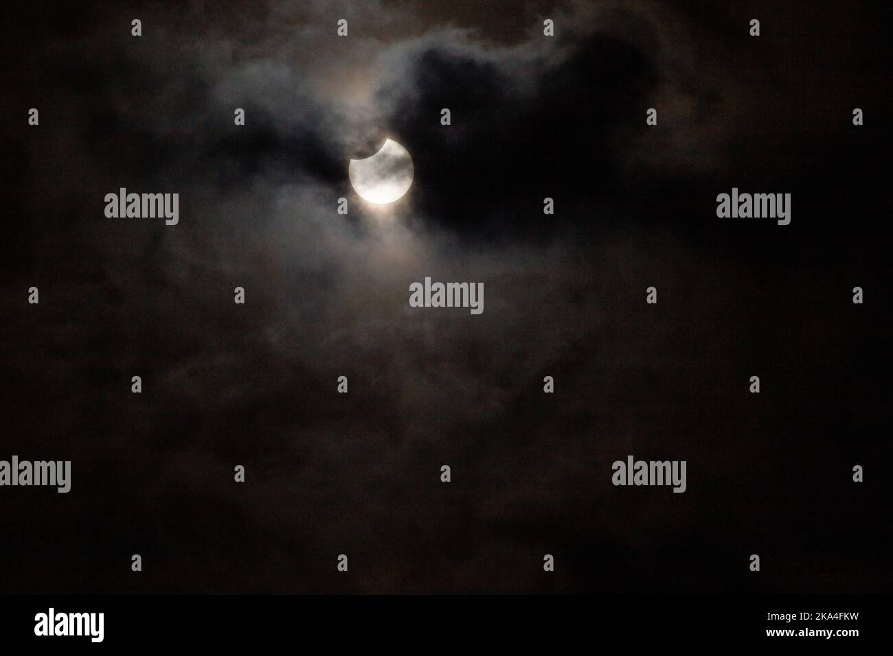 Partial solar eclipse with cloudy sky Stock Photo - Alamy