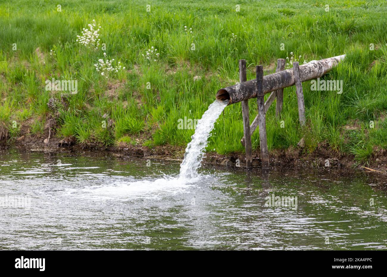 a pipe from which water flows in lake, river Stock Photo - Alamy