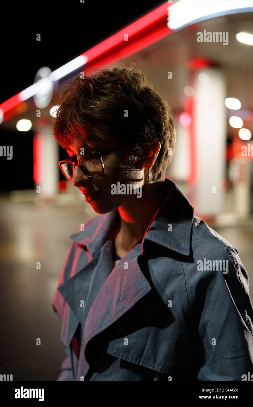 Calm sad young woman standing on city street in evening against ...