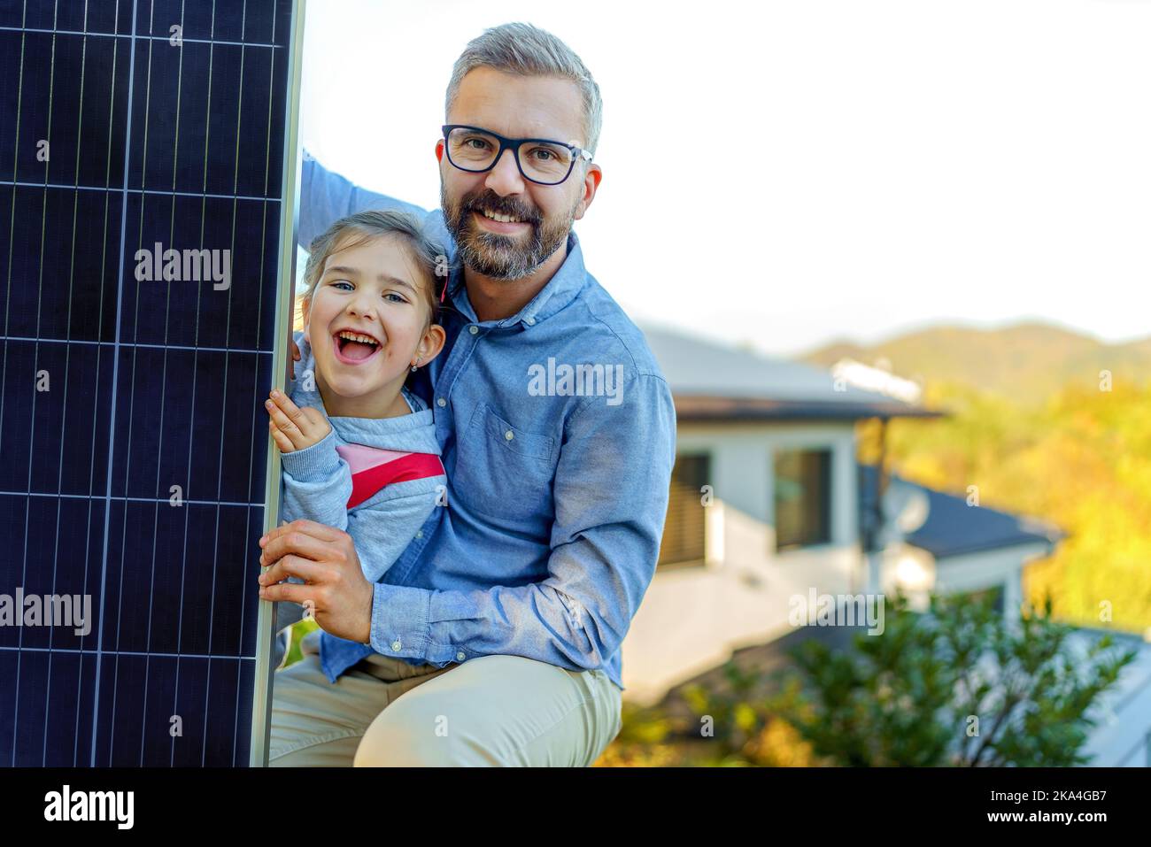Father with his little daughter near their house with solar panels ...