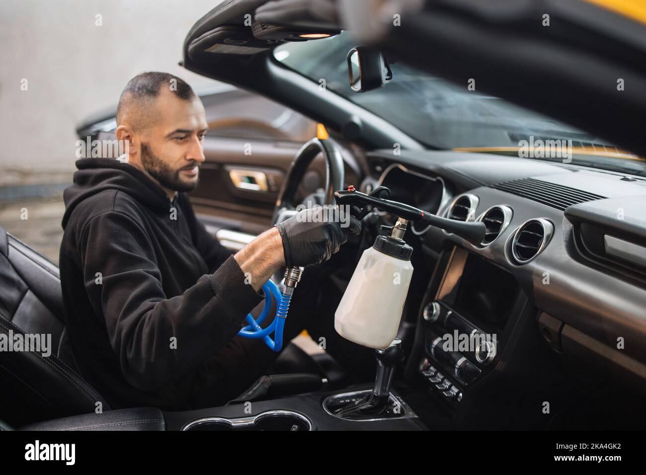Handsome male cleaner in black uniform and protective gloves, removing ...
