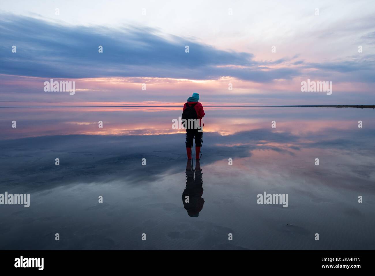 A beautiful shot of a man on a frozen lake with a reflection during the ...