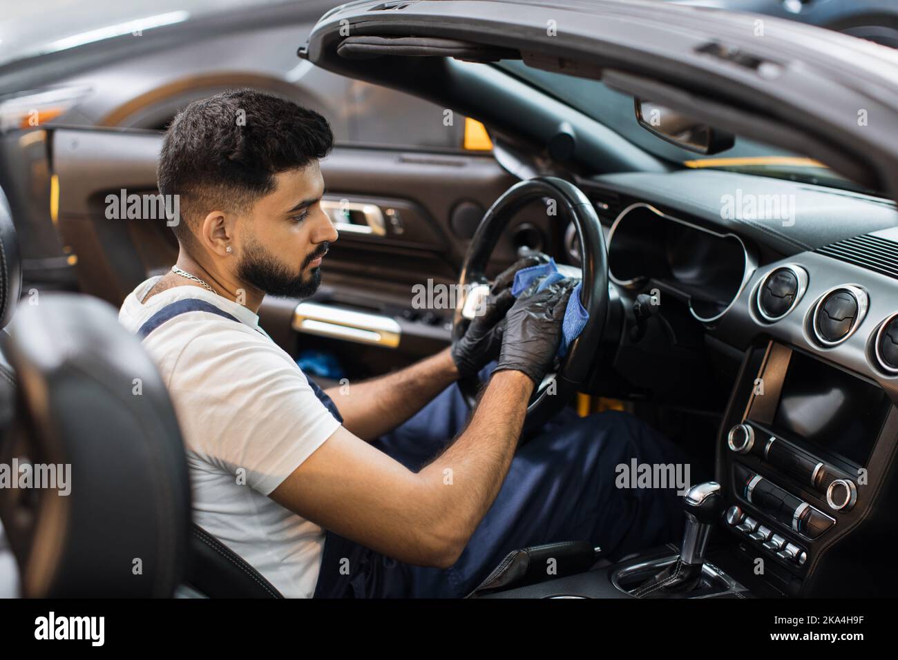 Handsome bearded young man in uniform and protective gloves, cleaning ...