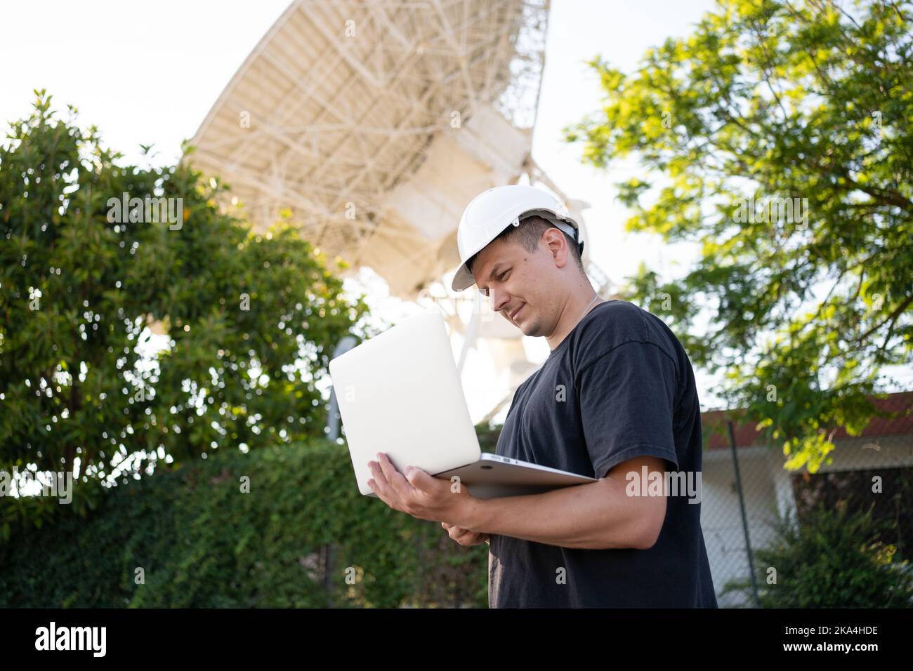 Engineer testing earth based astronomical radio telescope use laptop ...