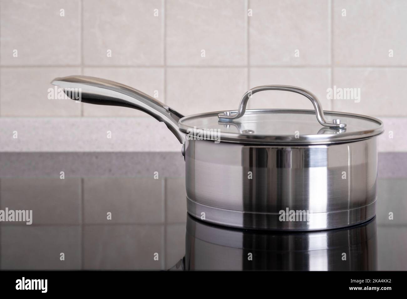 Stainless steel ladle sits on modern stove with glass-ceramic hob Stock ...