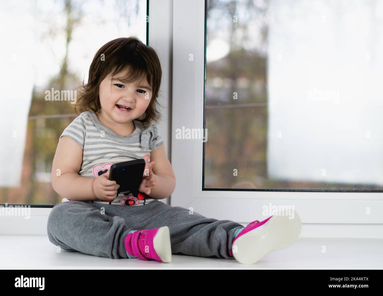 A close up of a cute little girl with phones trying to make a call ...