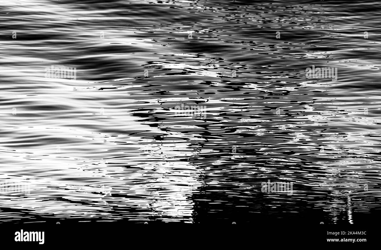 Reflection in a lake creates abstract patterns with light, shadows, and ...