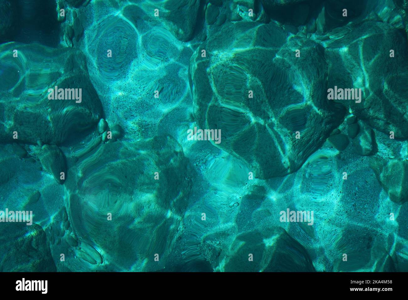 View from above to a stony seabed in clear water with abstract blue ...