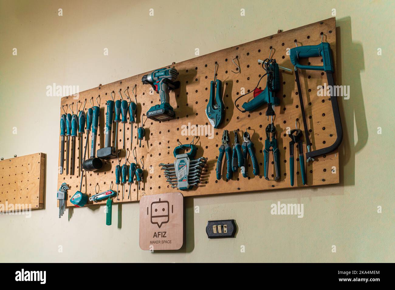 A set of tools in a workshop hung from a light yellow wall Stock Photo ...