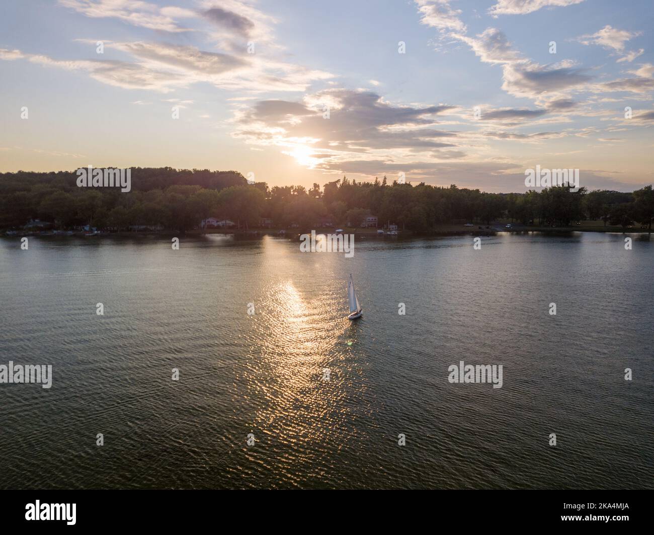 A bird's eye view of a boat sailing in the Owasco lake against green ...