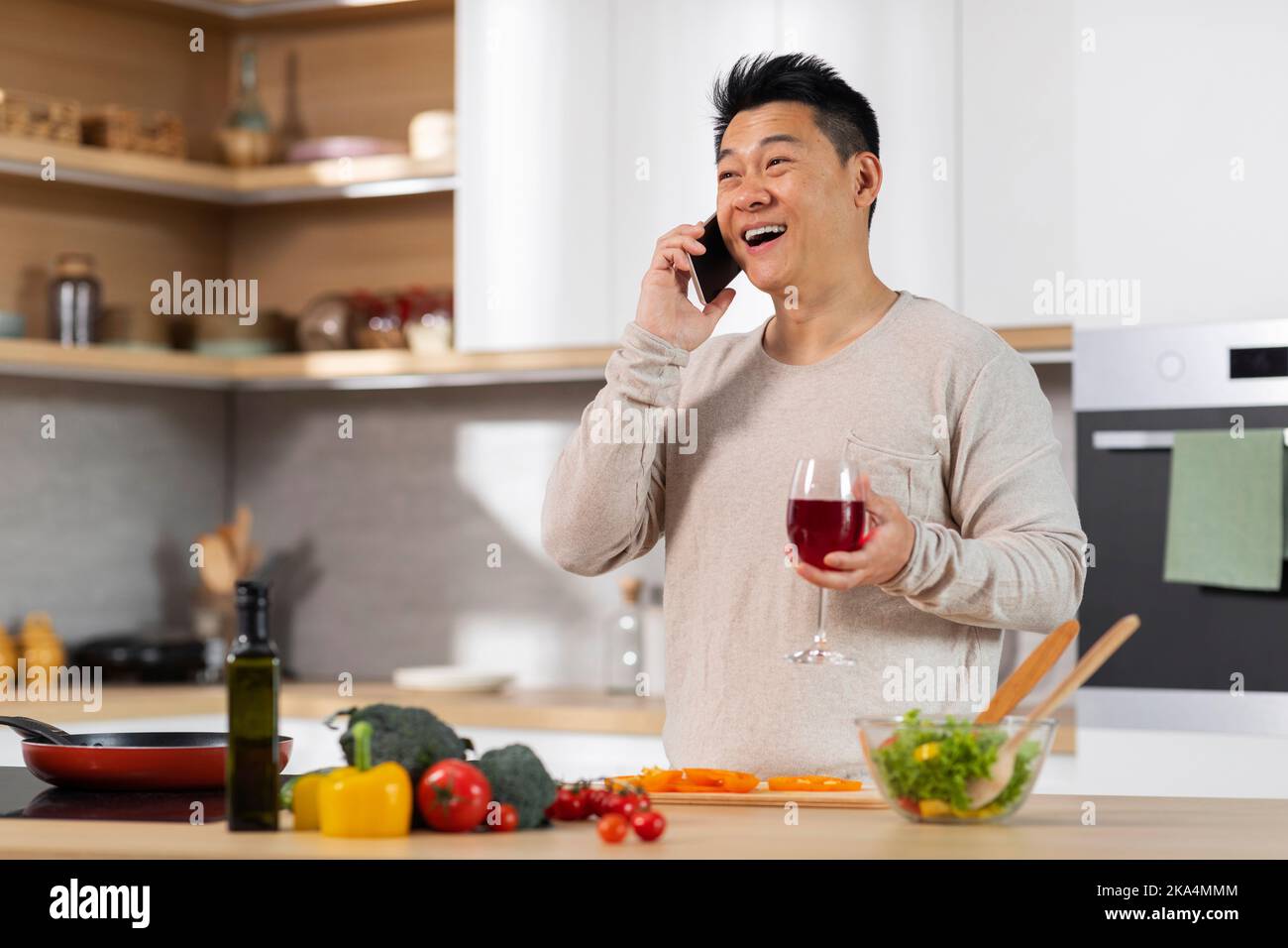 Happy asian man cooking meal and talking on phone Stock Photo - Alamy