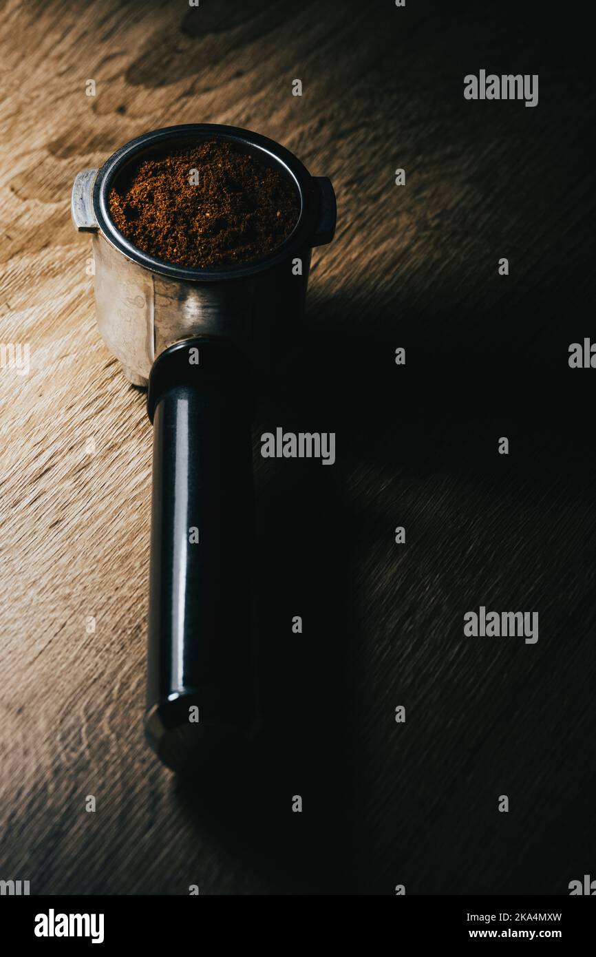 A closeup of Portafilter with smashed roasted coffee on a dark brown ...