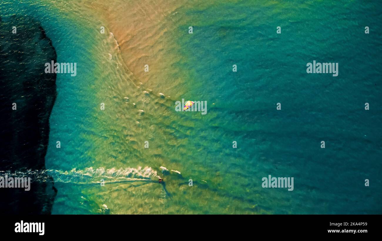 An aerial drone shot of a kite surfer surfing alone on the ocean waters ...