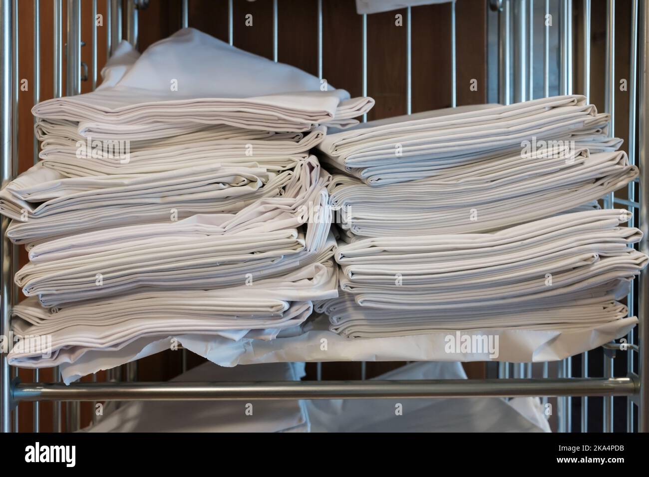 Bed linen, clean, ironed and stacked, on a shelf in a metal rack Stock ...