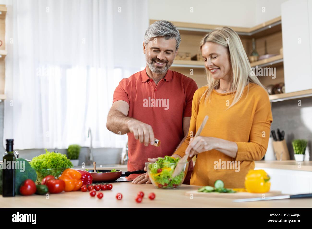 Cheerful loving spouses making healthy vegetable salad together Stock ...