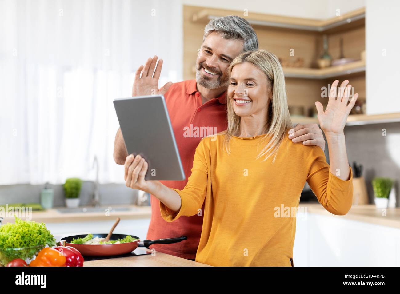 Positive man and woman cooking and having video call Stock Photo - Alamy