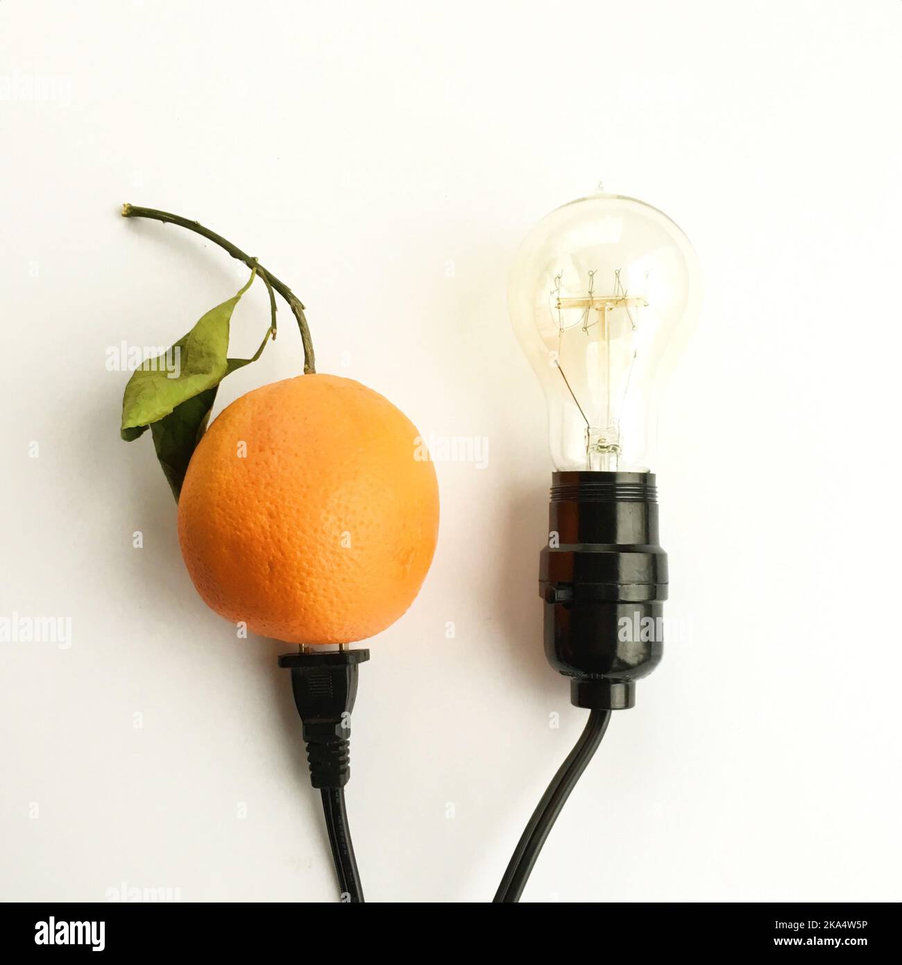 Light bulb plugged into an orange to illustrate Food generating clean ...
