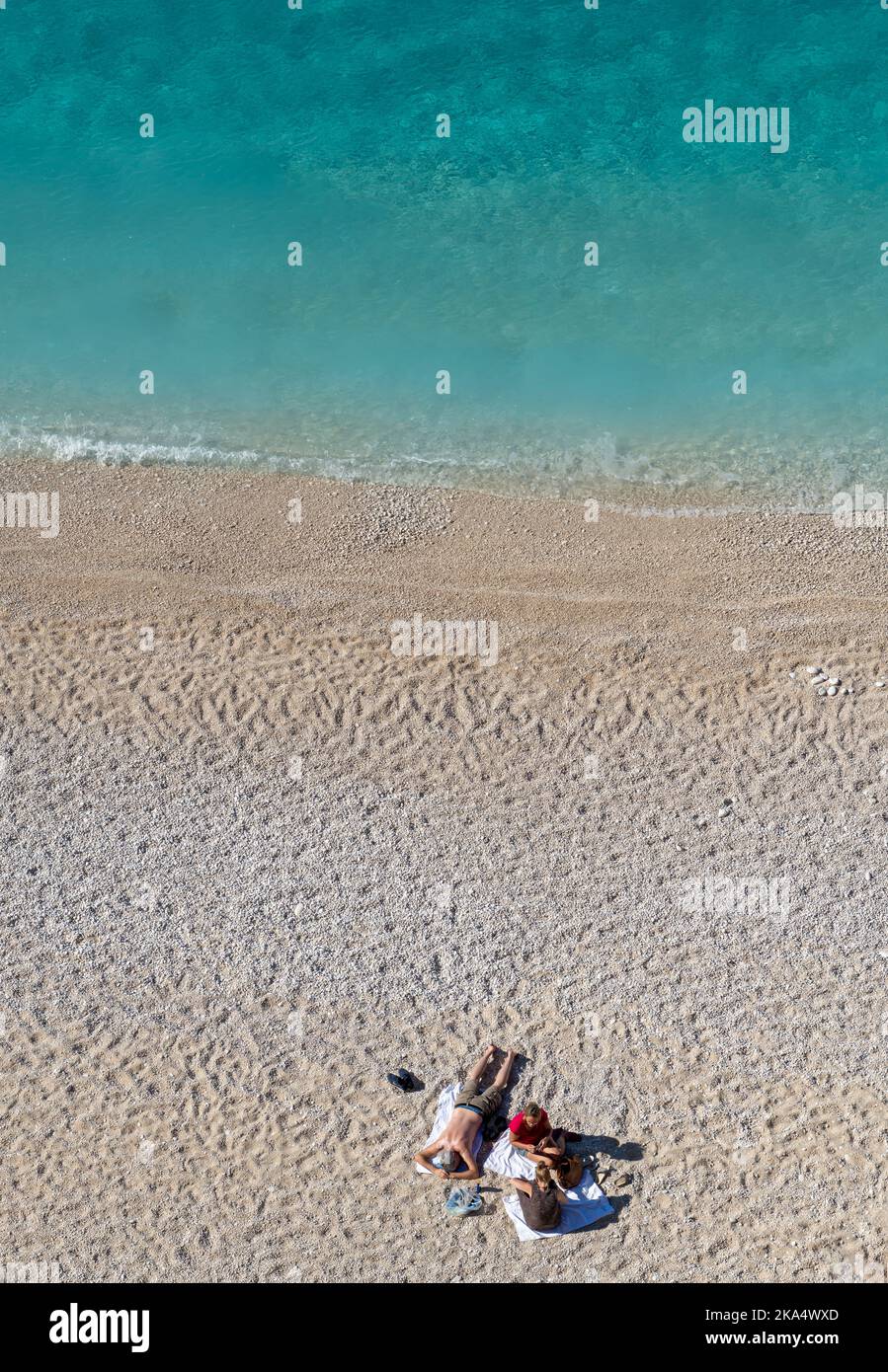 A beautiful sandy beach with crystal clear water with a couple enjoying ...