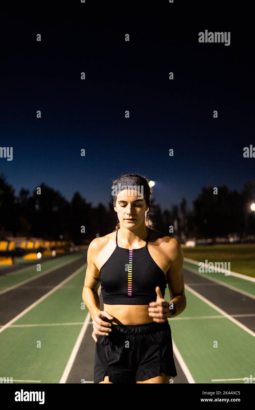 woman running on a running track at night Stock Photo - Alamy